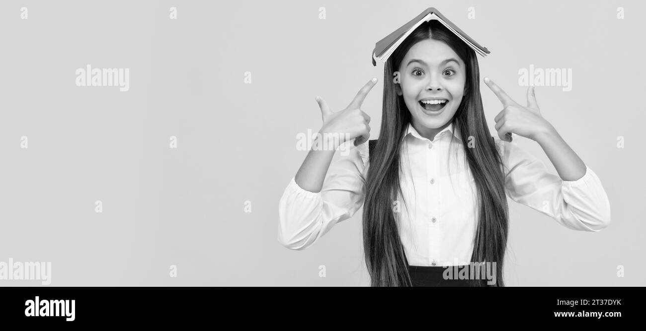 happy teen girl in school uniform pointing finger book on head, learn ...