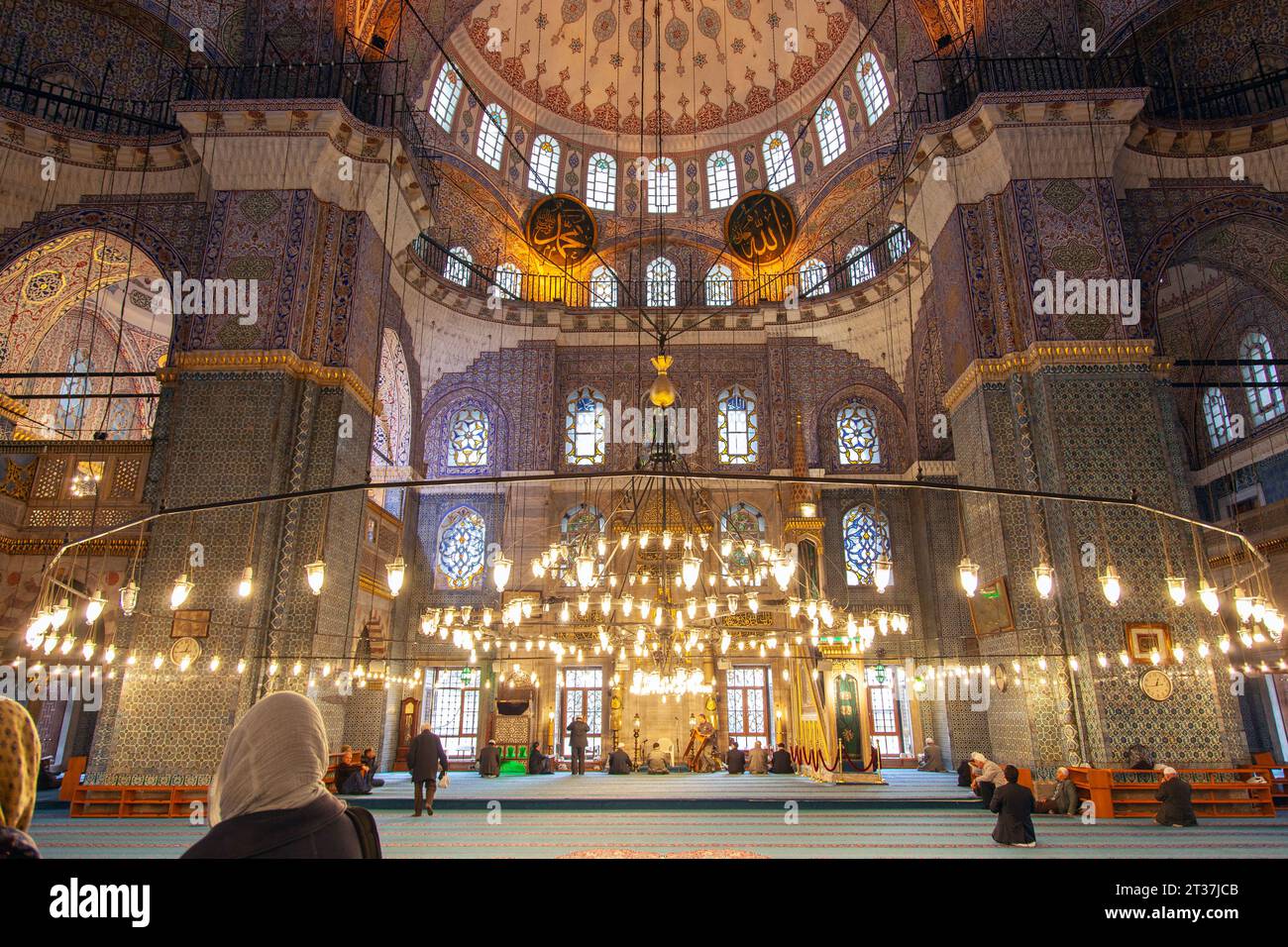 People praying inside the lit up 17th Century Blue Mosque, an Ottoman-era historical imperial ...