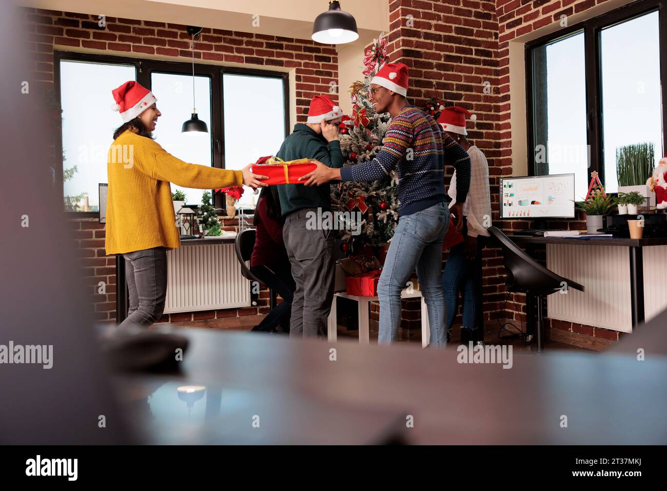 Smiling diverse colleagues exchanging christmas gifts at corporate party in decorated festive ...