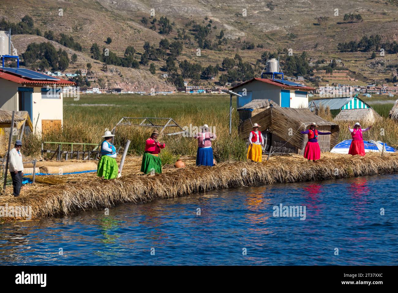 Women from floating islands of the Uros community welcoming tourists ...