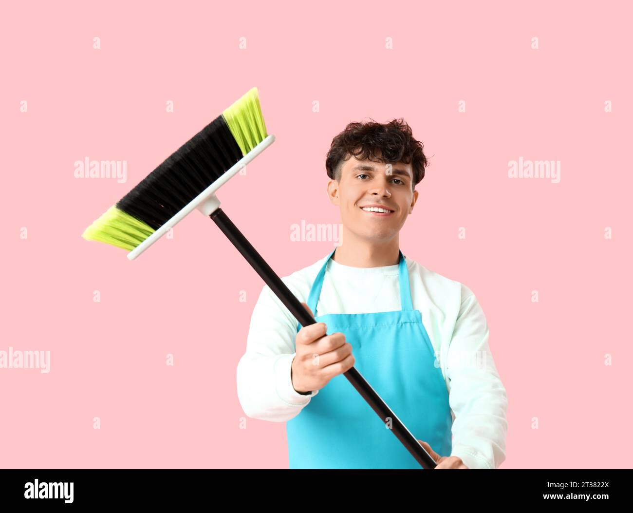 Male janitor with broom on pink background Stock Photo - Alamy
