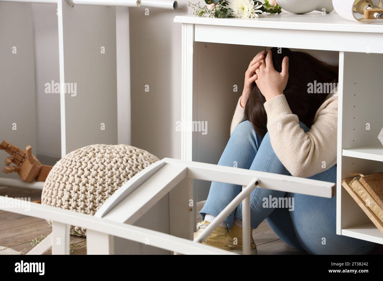Young woman hiding under table during earthquake at home Stock Photo ...