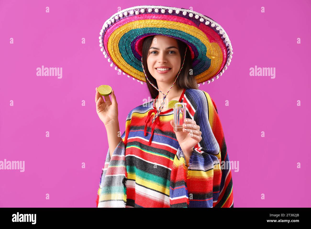 Beautiful young Mexican woman with tequila and lime on magenta ...