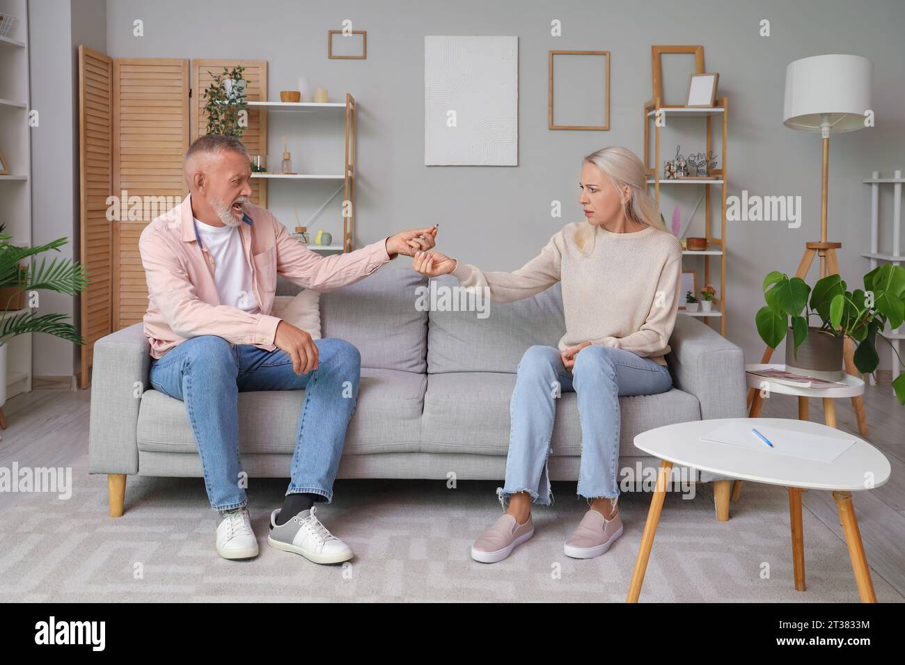 Mature couple giving each other wedding rings at home. Divorce concept ...