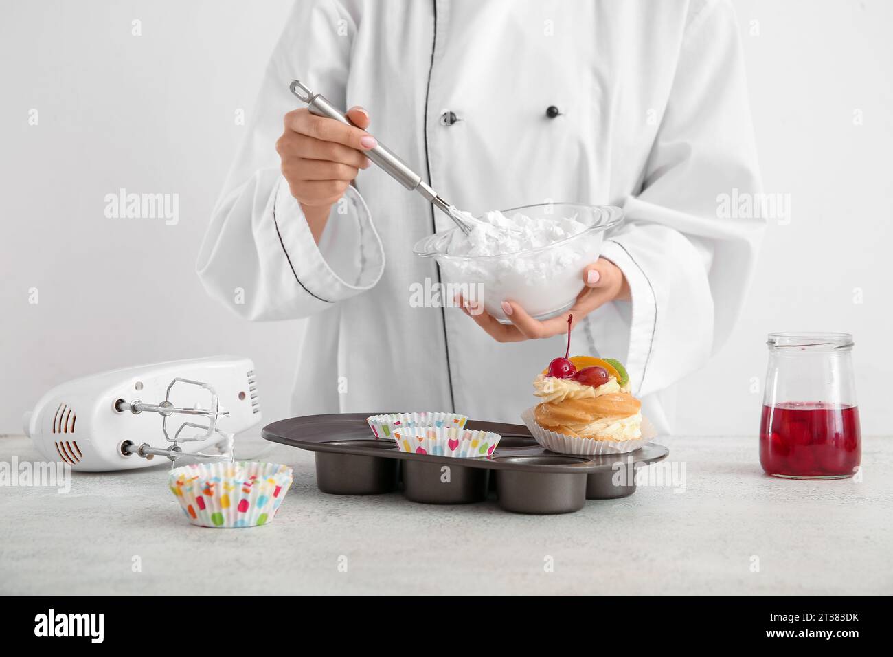 Female confectioner cooking tasty cakes on white background Stock Photo ...