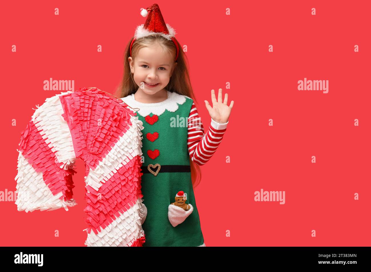Cute little girl in Christmas elf costume with candy cane pinata waving ...