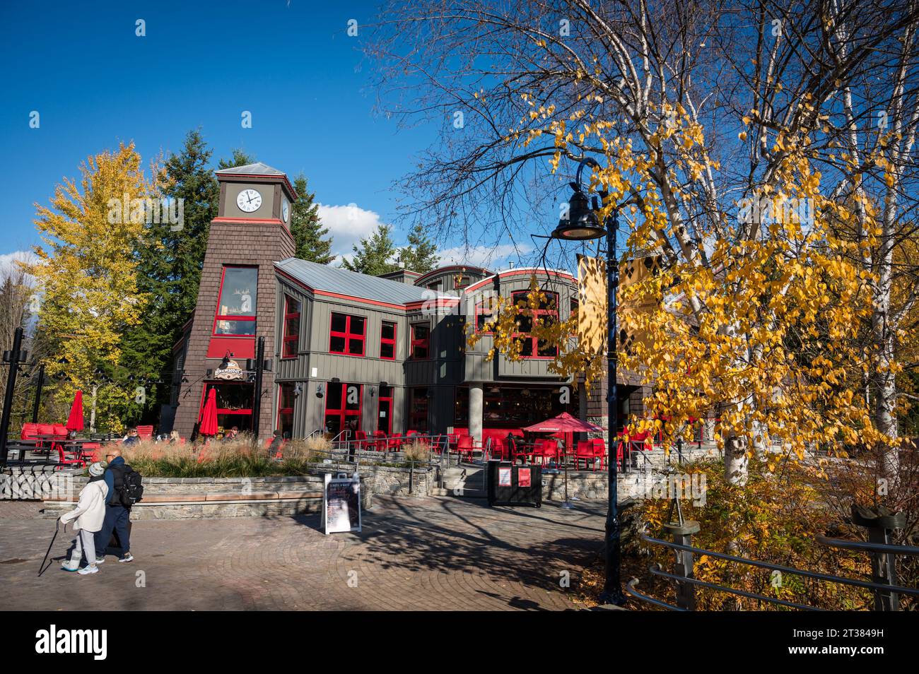 Tourists stroll through the Whistler village on a crisp fall day. Fall colours on the trees and ...
