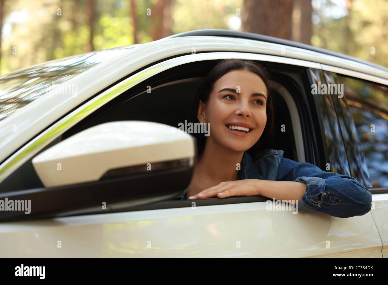 Happy young woman looking out of car window, view from outside ...