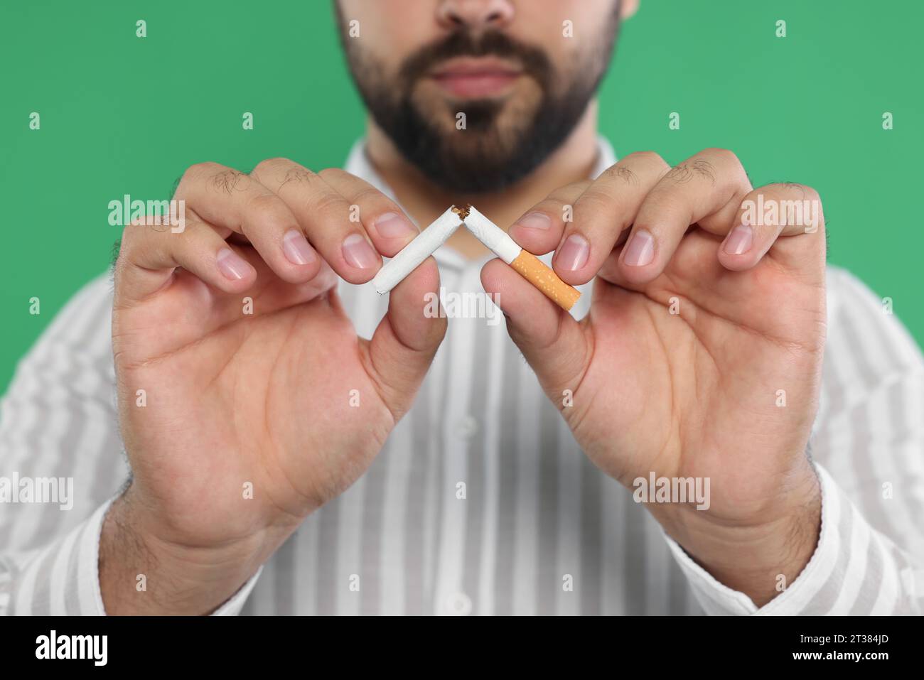 Stop smoking concept. Man breaking cigarette on green background ...