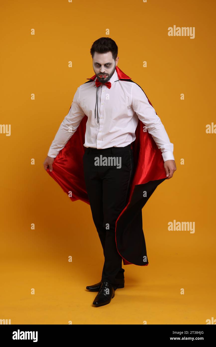 Man in scary vampire costume with fangs on orange background. Halloween ...