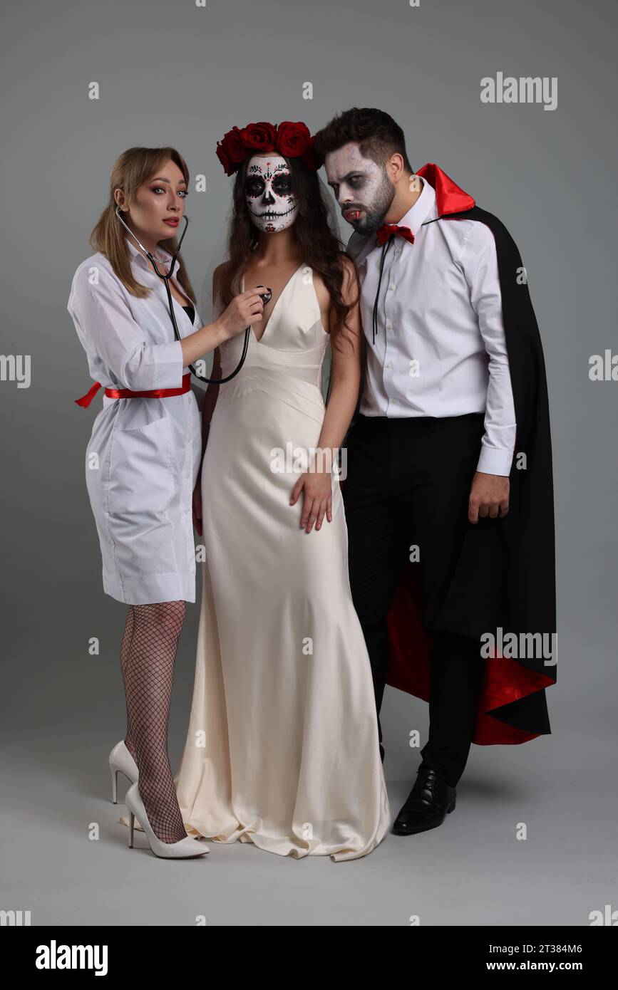Group of people in scary costumes on light grey background. Halloween ...