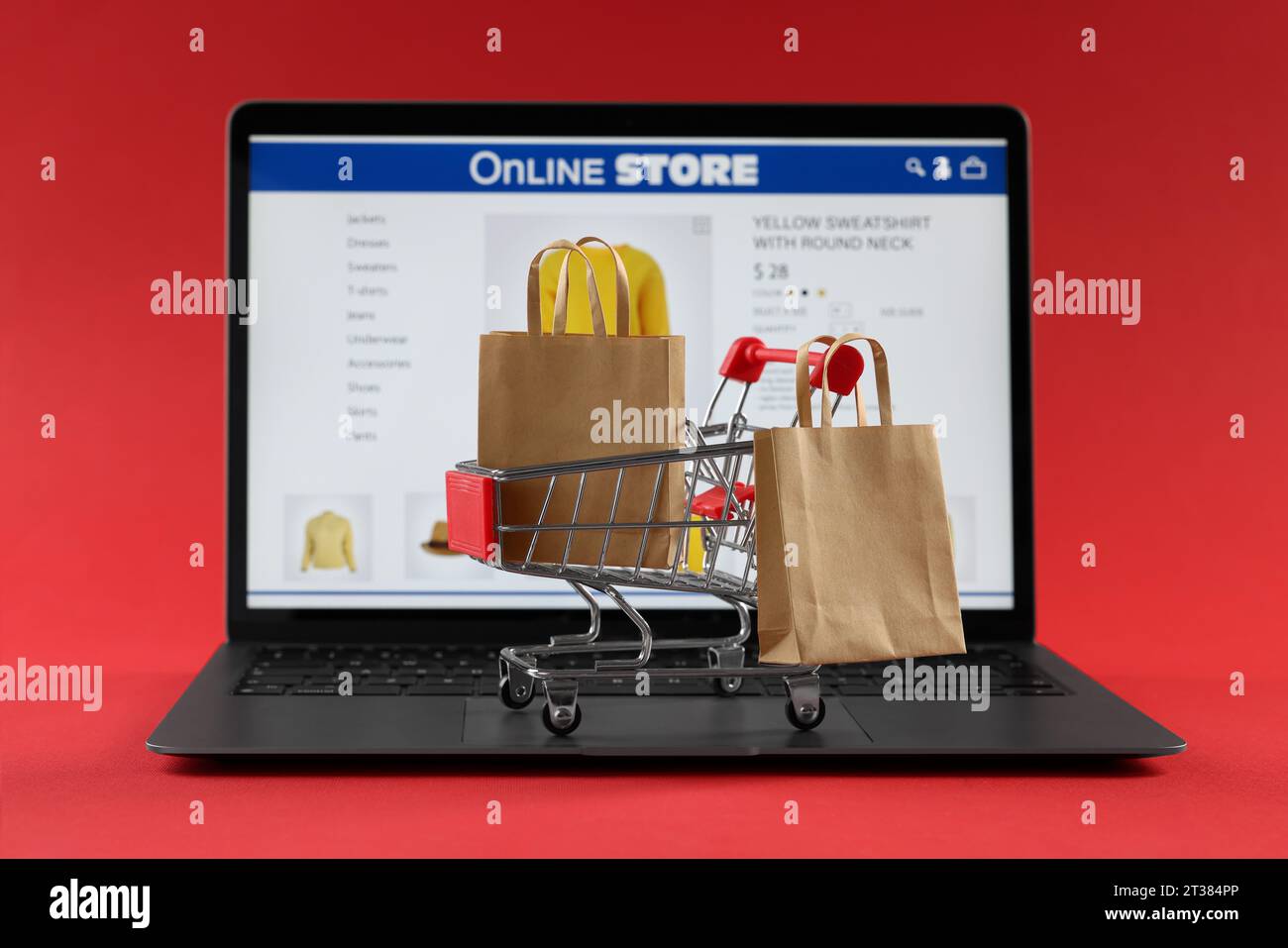 Online store. Laptop, mini shopping cart and paper bags on red ...
