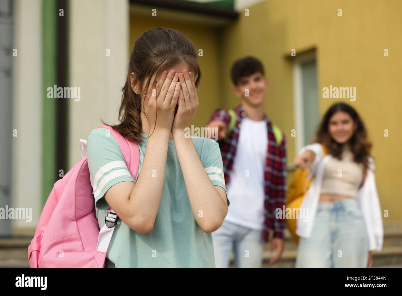 Teen problems. Students pointing at upset girl outdoors, selective ...