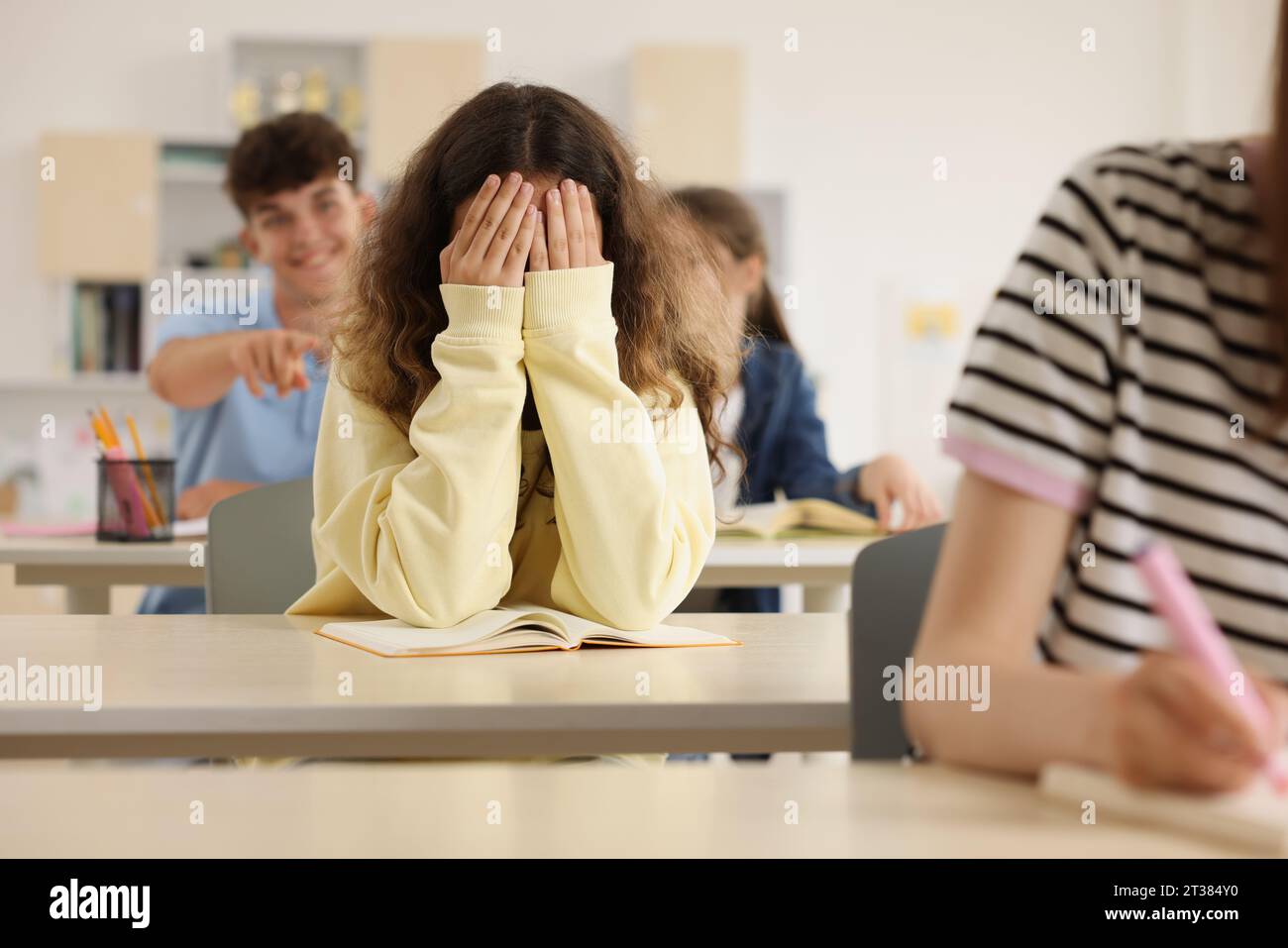 Teen problems. Lonely girl sitting separately from other students in ...