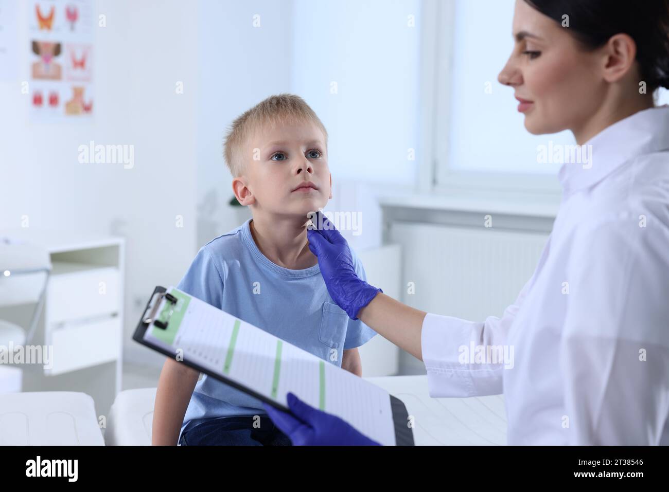 Endocrinologist with clipboard examining boy's thyroid gland at ...