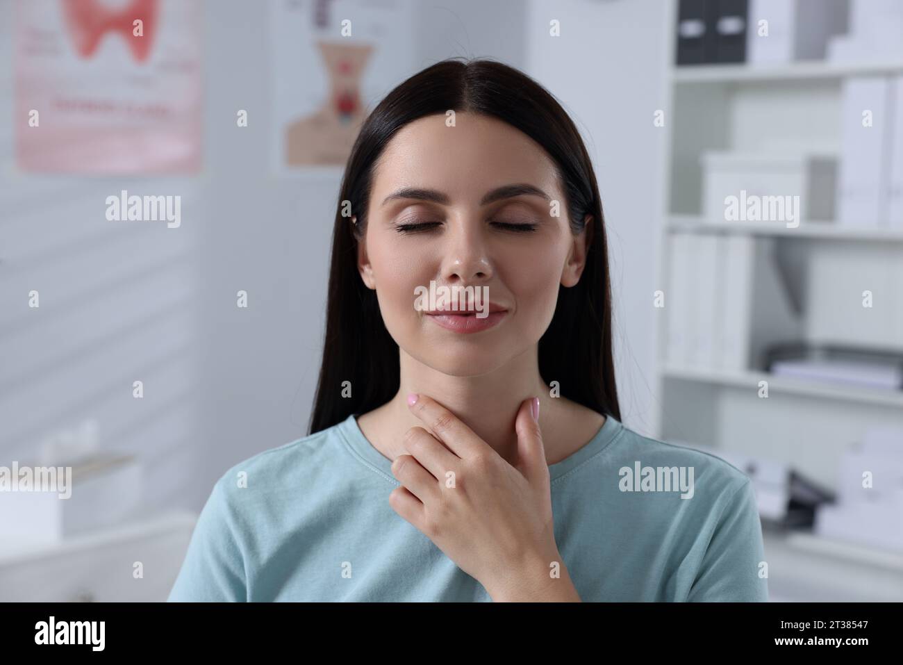 Endocrine system. Young woman doing thyroid self examination indoors ...