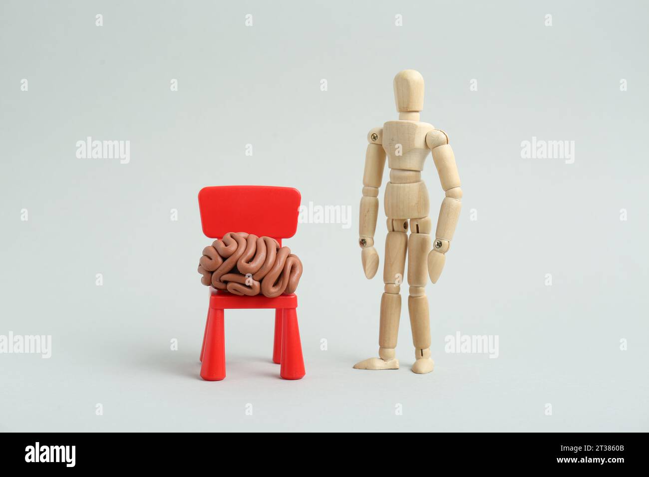 Mini chair with brain made of plasticine and wooden human model on ...
