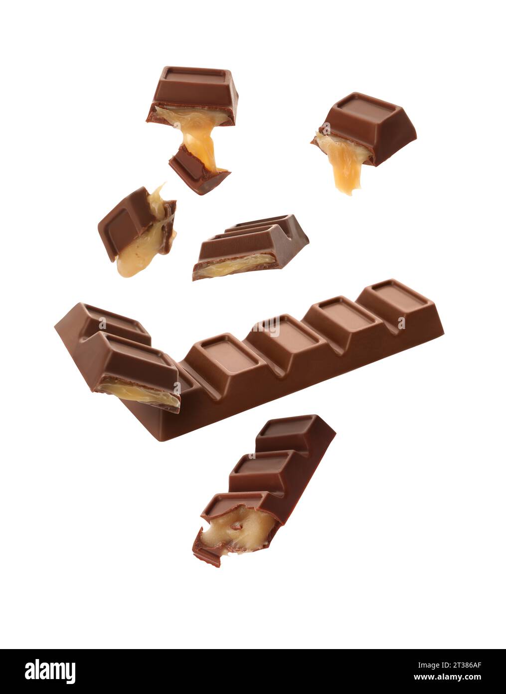 Whole and broken chocolate bars with caramel falling on white ...