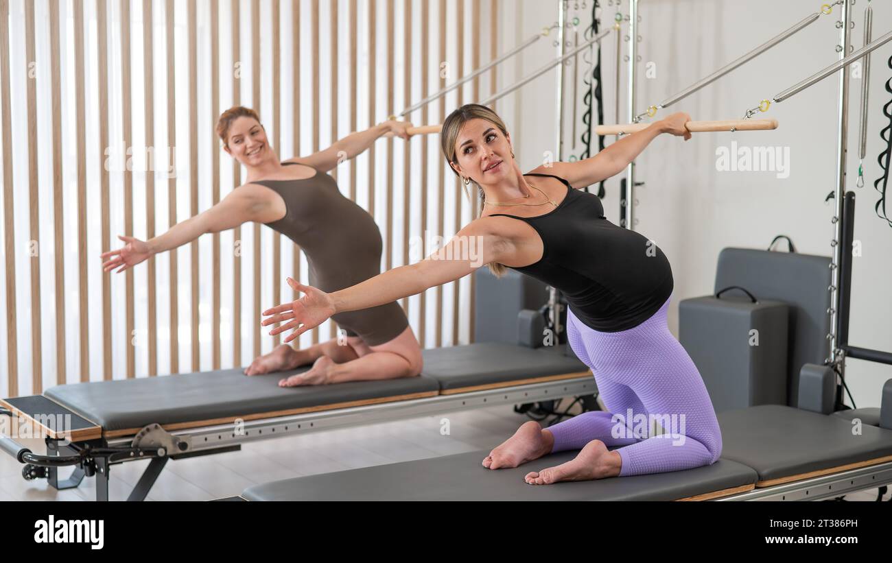 Two pregnant women do Pilates exercises on a reformer Stock Photo - Alamy