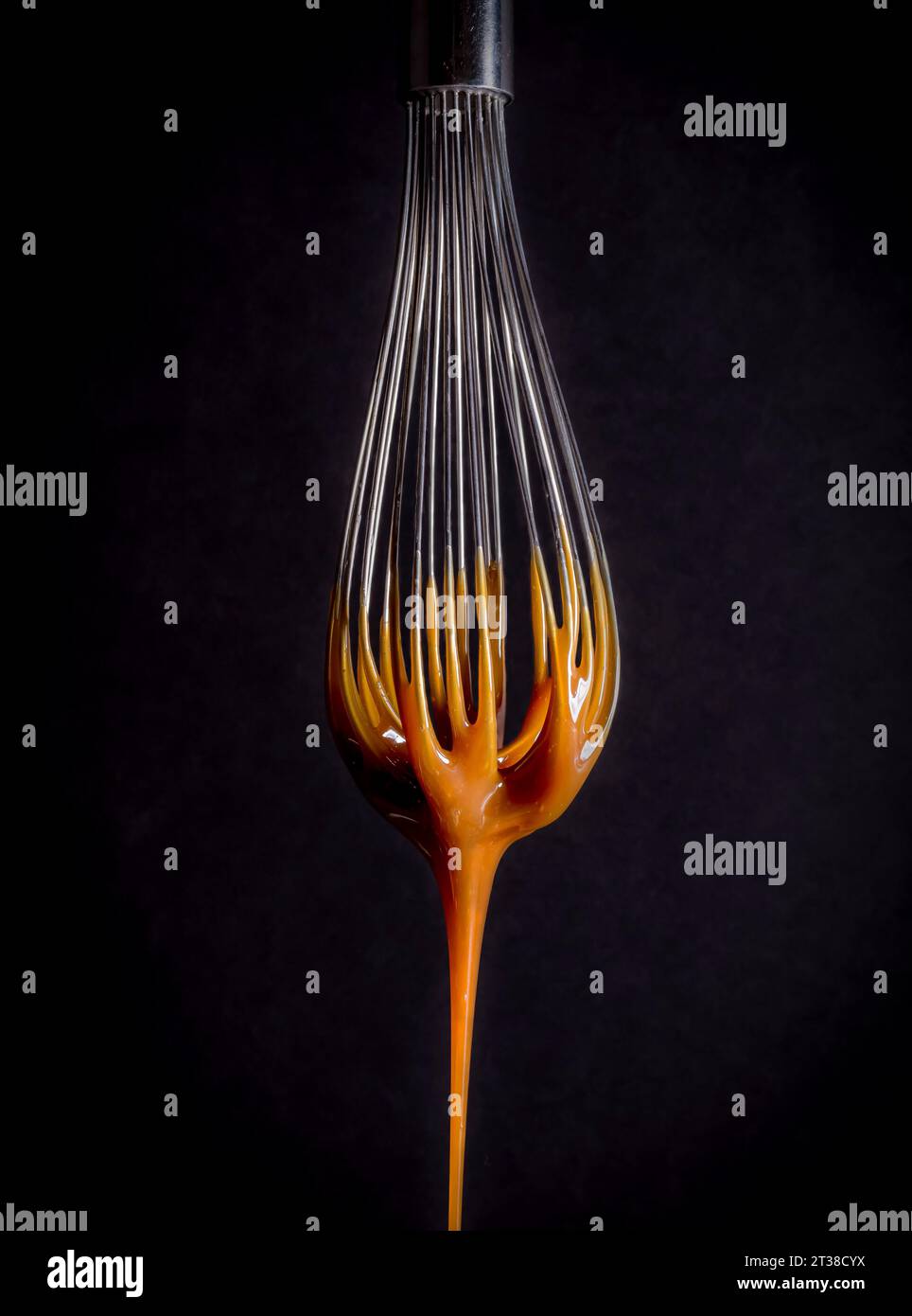 Caramel dripping from whisk on black background Stock Photo - Alamy