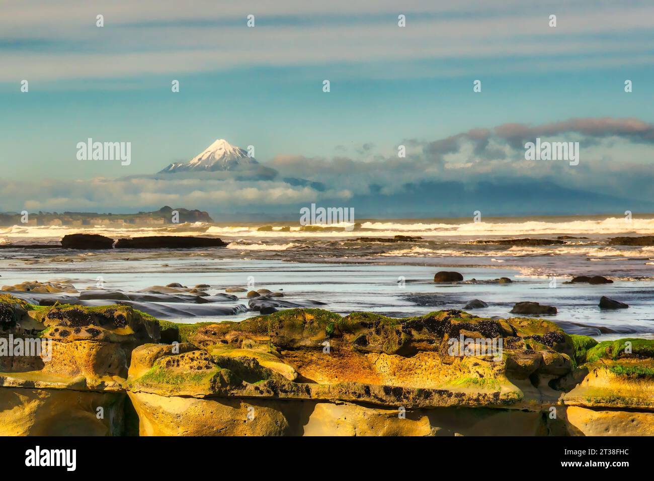 Snow capped volcanic peak of Mount Taranaki shrouded in cloud viewed ...