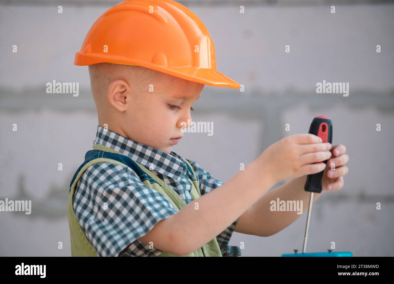 Kid boy twists bolt with screwdriver. Child repairman with repair tool ...