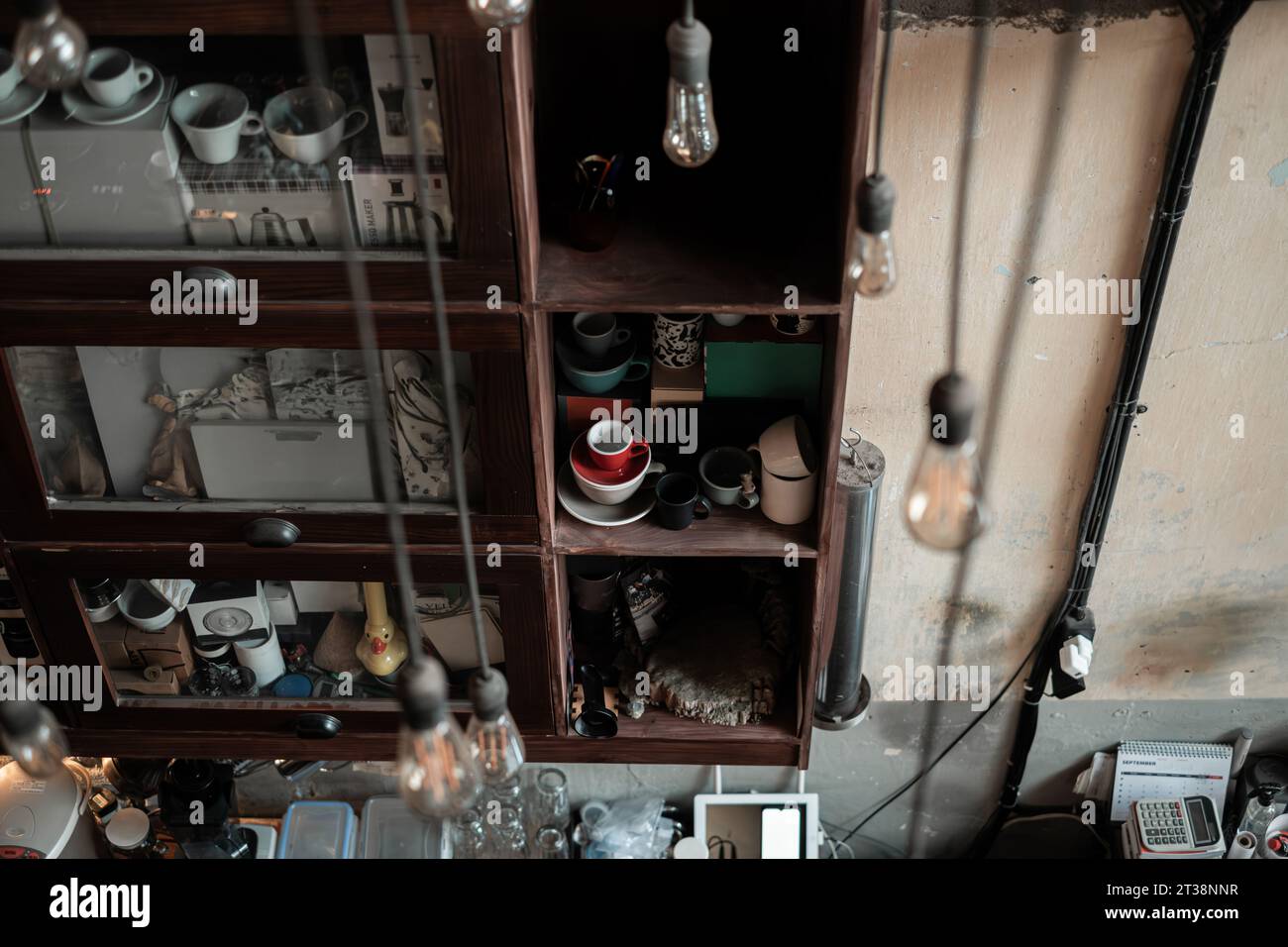 A Shelf Contains Cluttered Cups Mugs And Various Objects Of Different Sizes And Colors In