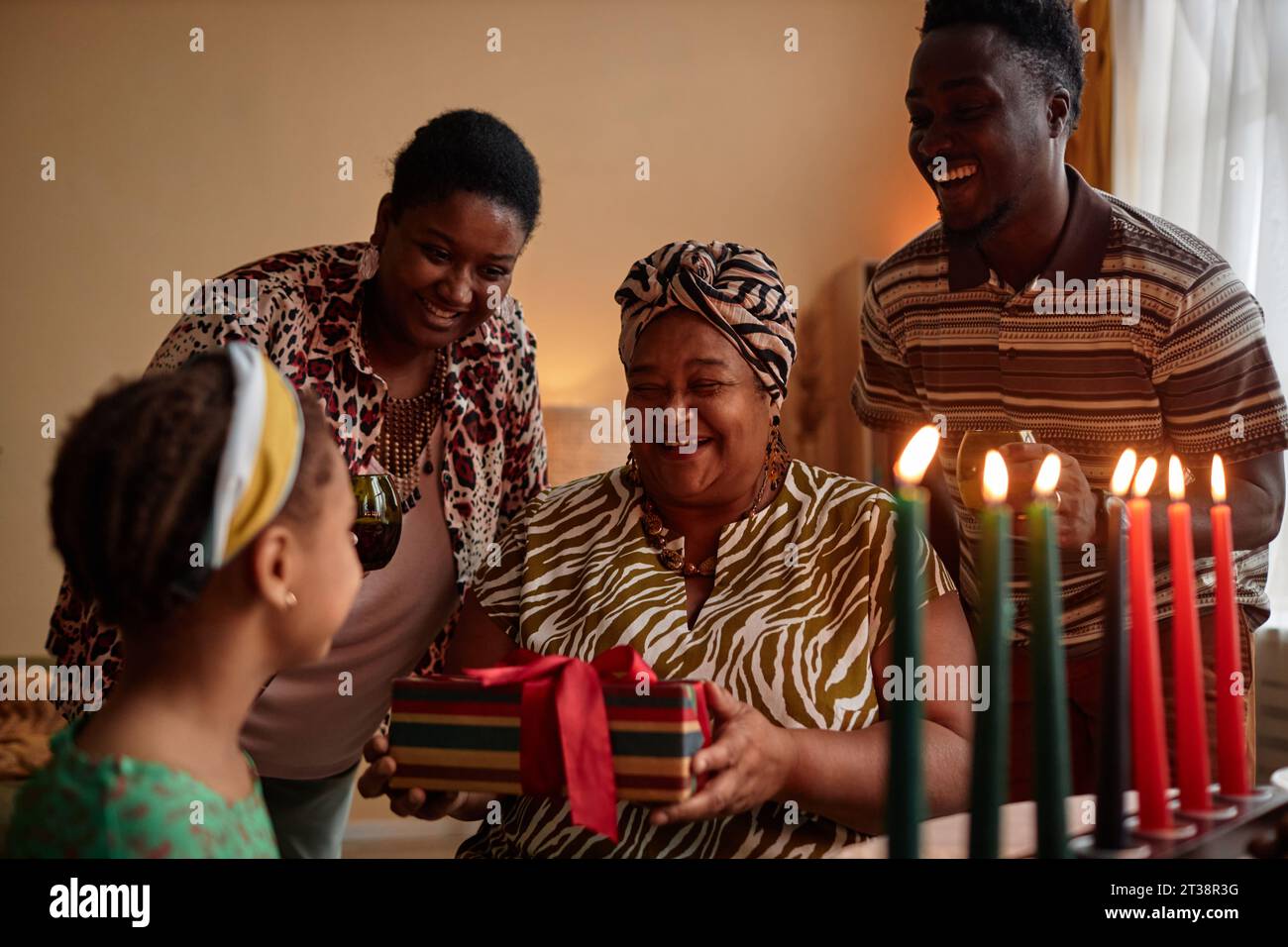 Black family giving present to preteen girl at Kwanzaa celebration ...