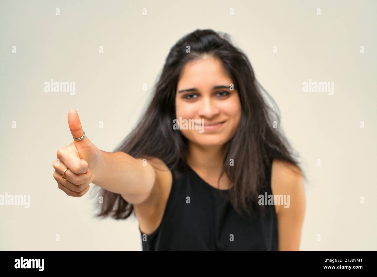Displaying a sign of affirmation, a gleaming woman with dark, cascading ...