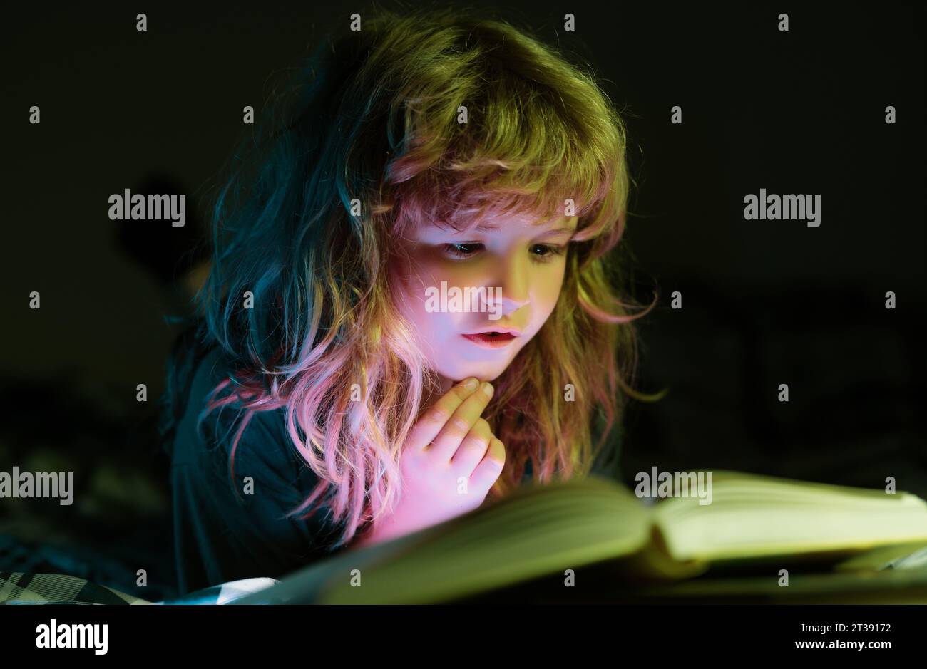 Child reading a book in bed before going to sleep. Little boy lying on ...