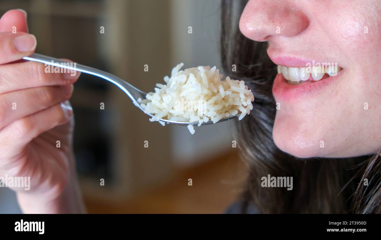A female adult wearing a white shirt and blue jeans is enjoying a bowl ...