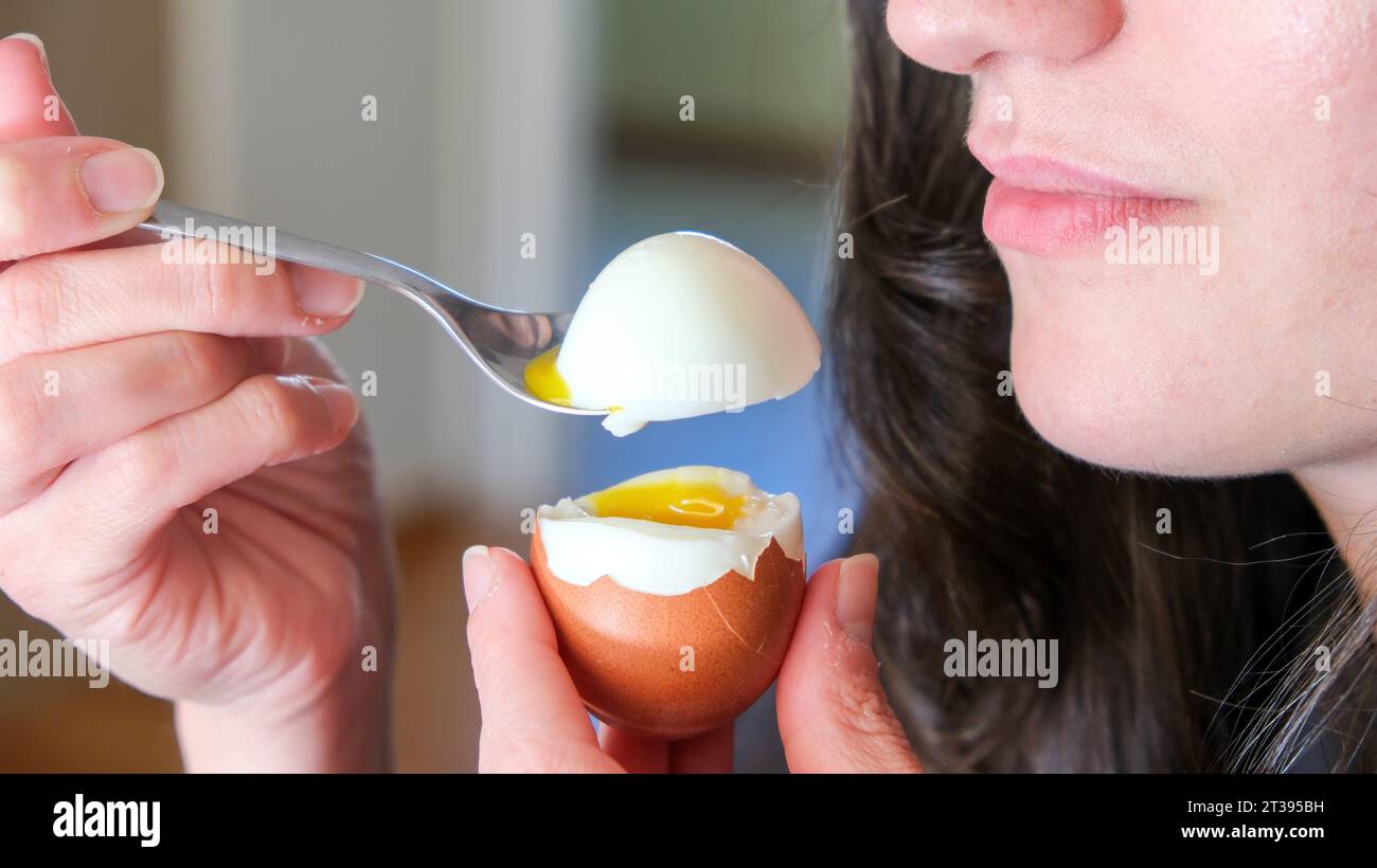 A woman is holding a boiled egg in one hand while the other hand is ...