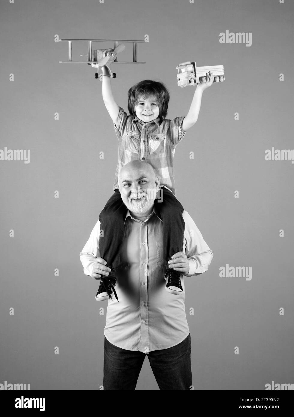 Young grandson and old grandfather with toy plane and wooden toy truck ...