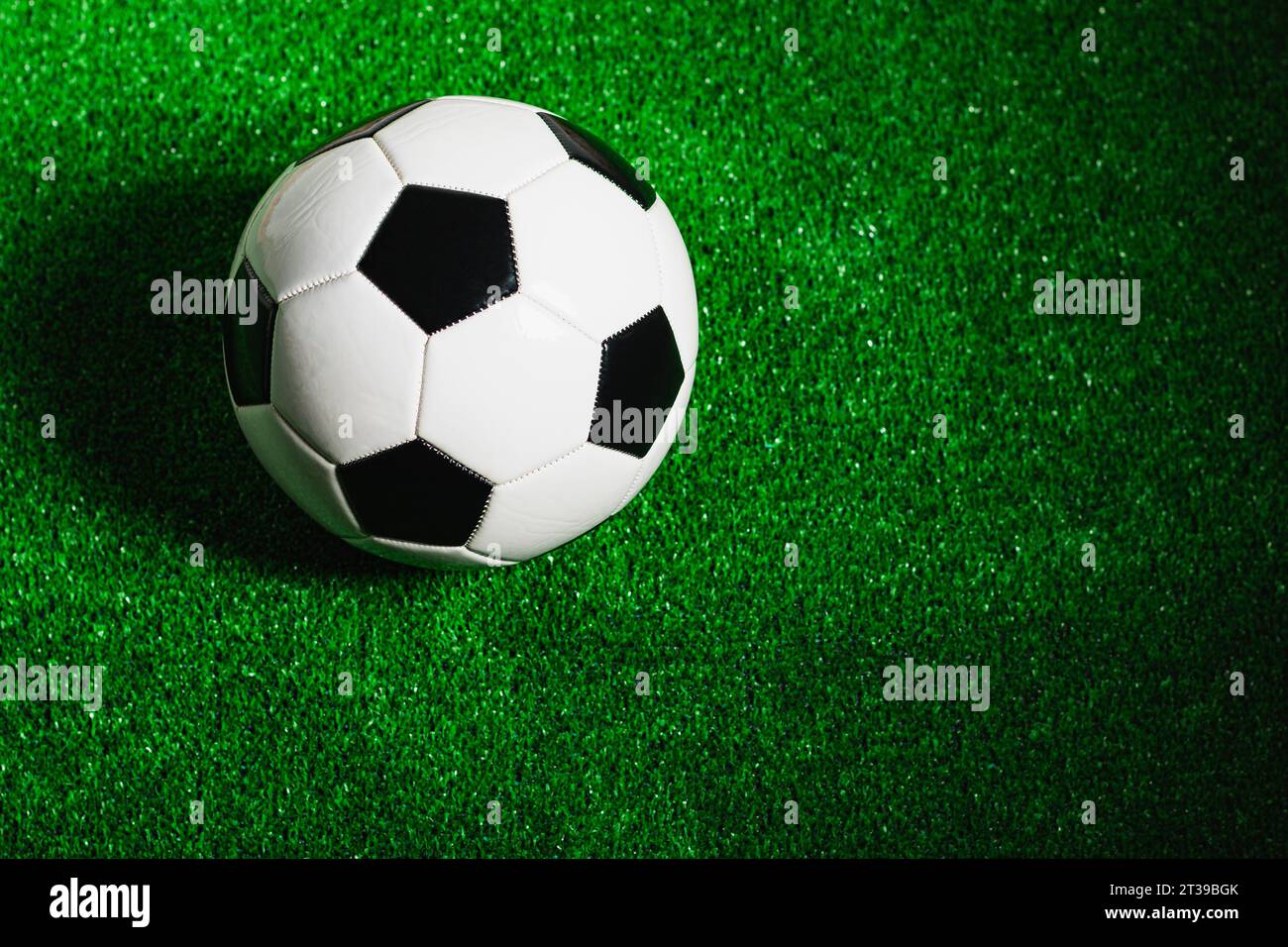 A classic black and white soccer ball isolated on green grass seen from ...