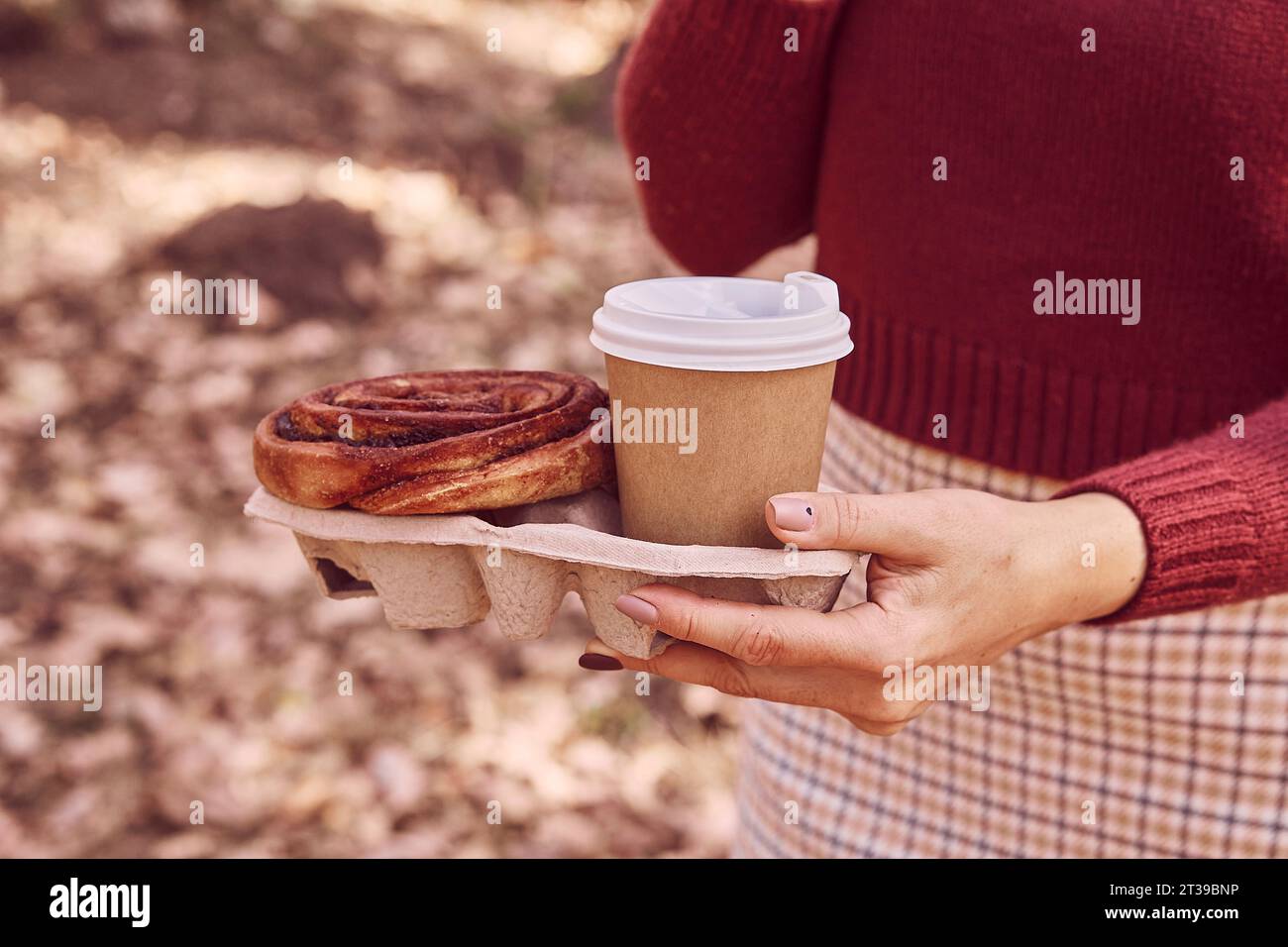 Woman walking in the park with cinnabon bun and coffee. Aesthetic ...
