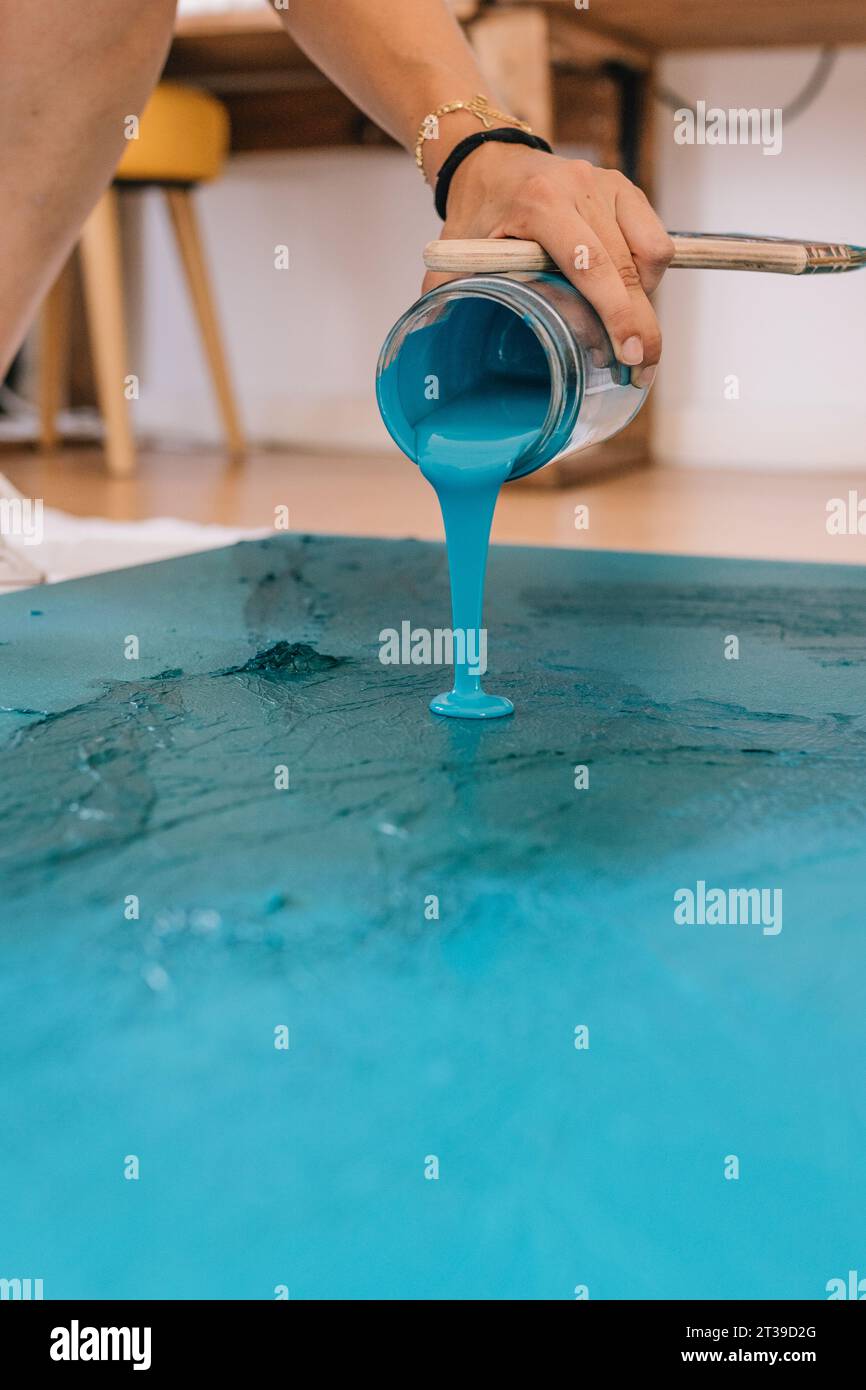 Crop unrecognizable professional female painter pouring blue liquid ...