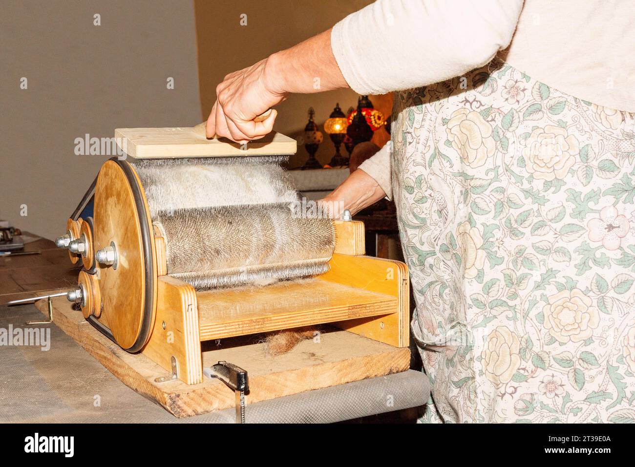 Anonymous woman working with a hand-operated drum carder, preparing ...