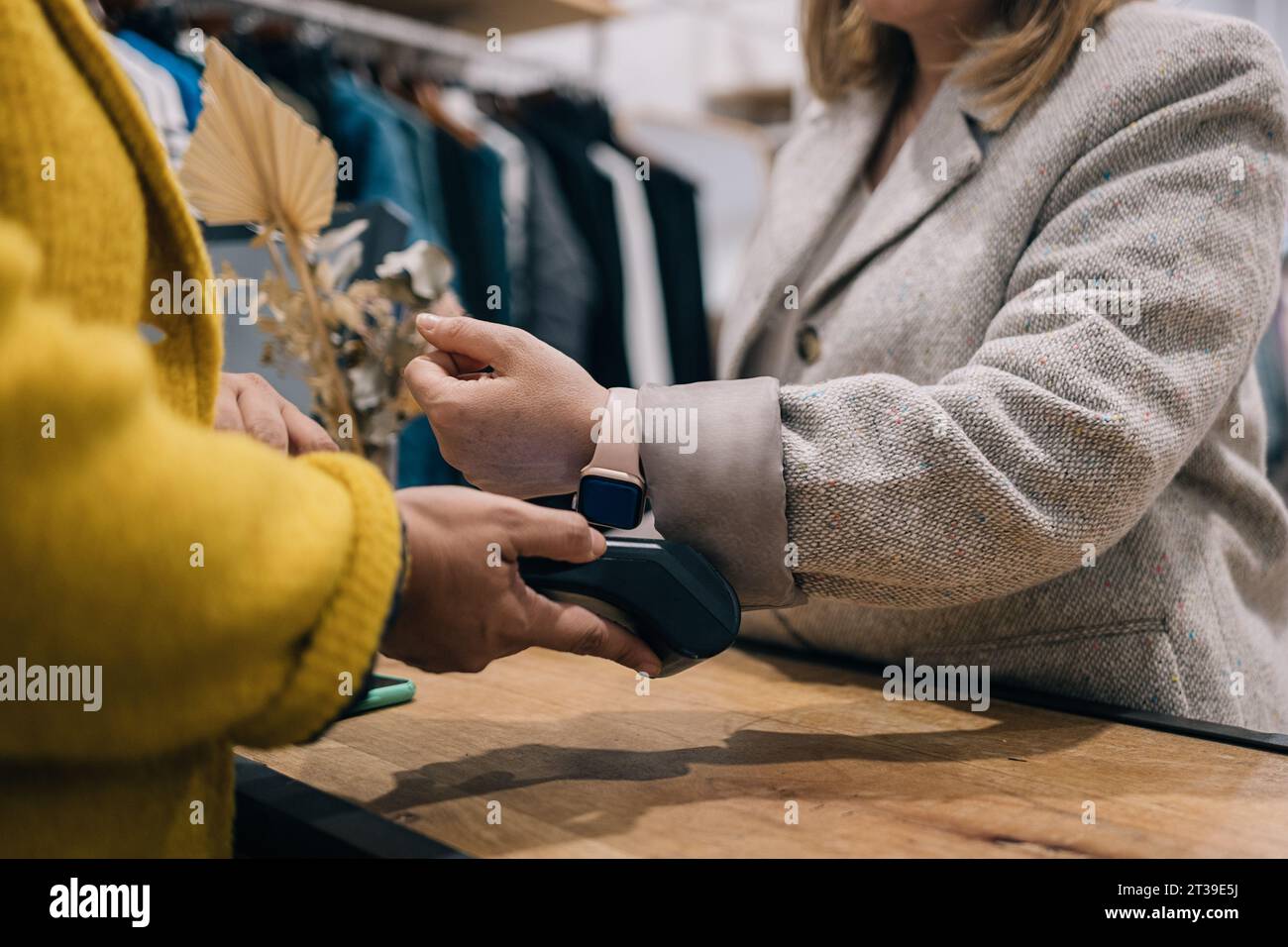 Close-up of a customer making a contactless payment to a store owner ...
