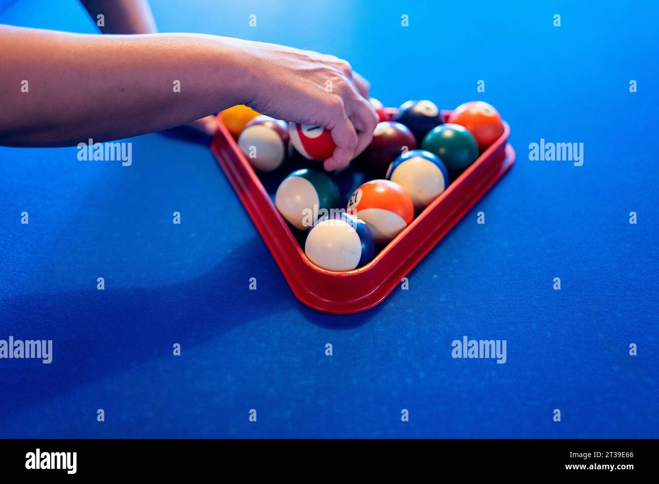 Crop anonymous person placing colorful pyramid of billiard balls in ...