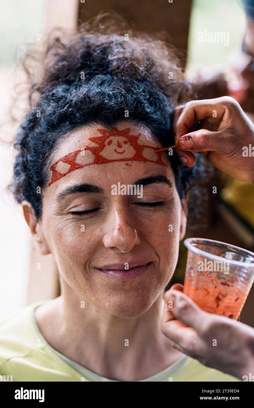 Crop anonymous person applying traditional tribal paint on forehead of ...