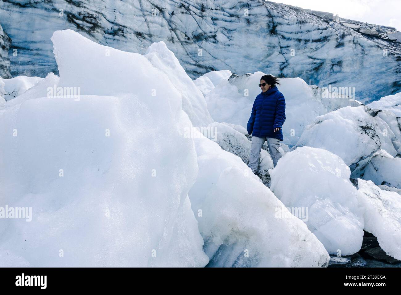 An individual clad in a blue jacket stands among towering ice ...