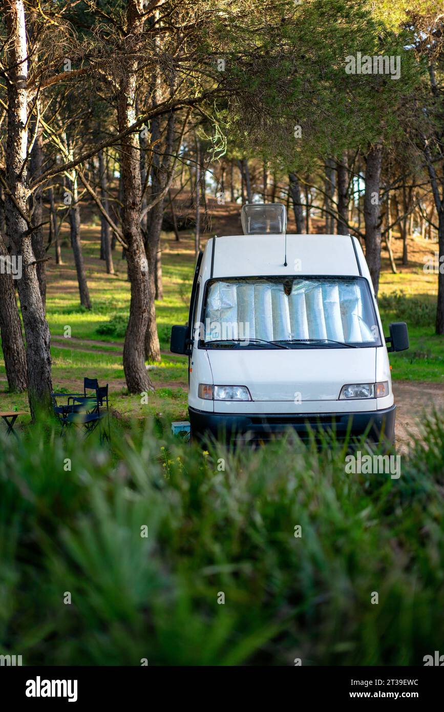 White camper van parked near trees with camp table chairs on grass ...