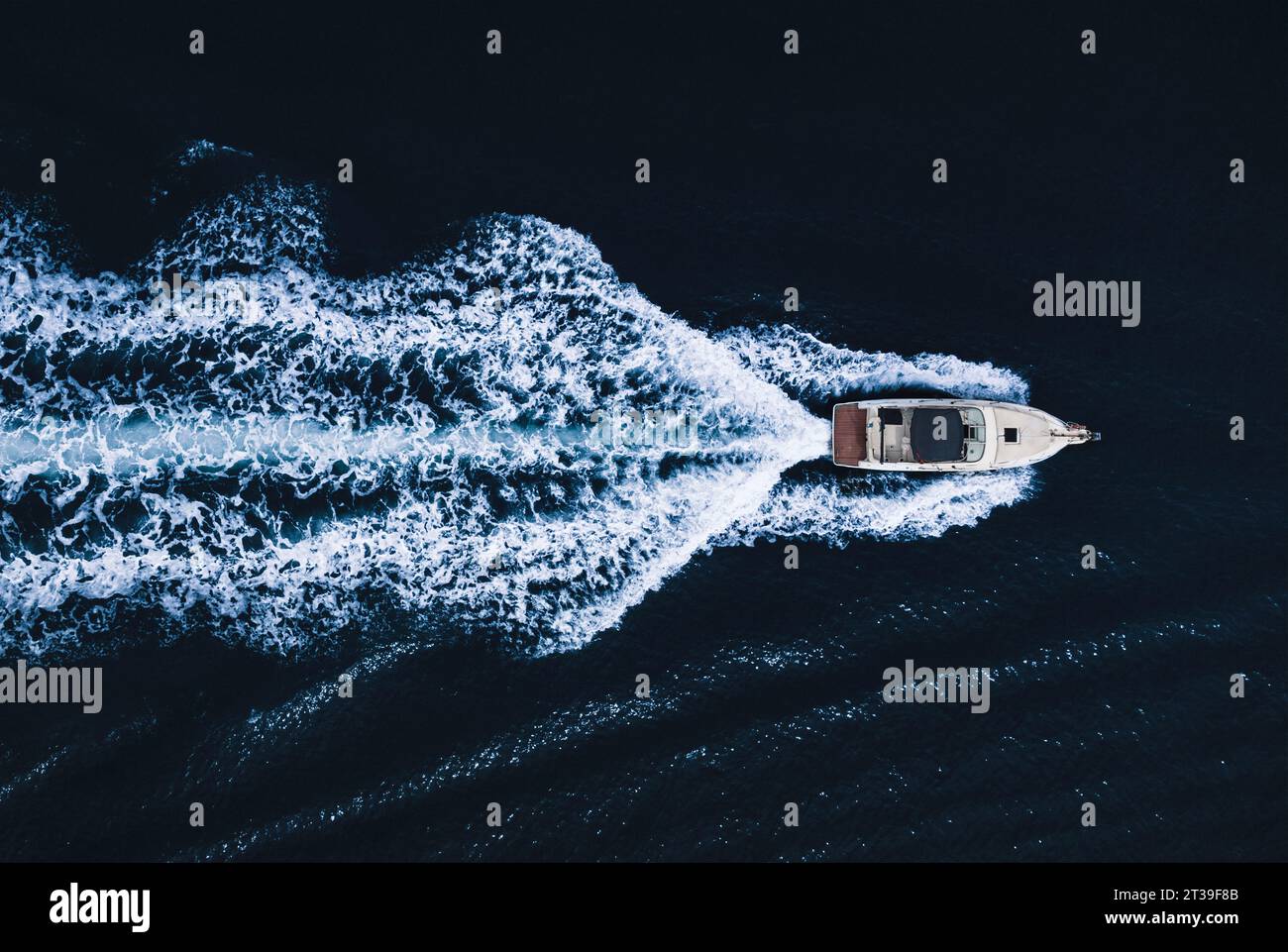 Top drone view of trail on water surface behind fast moving white ...