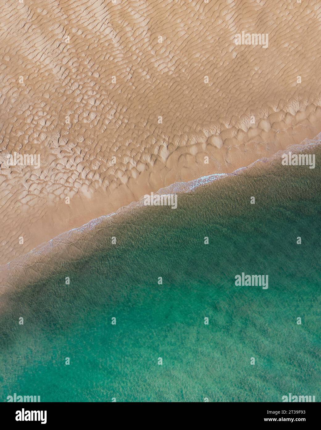 Aerial top view of turquoise ocean washing sandy beach with rippled ...
