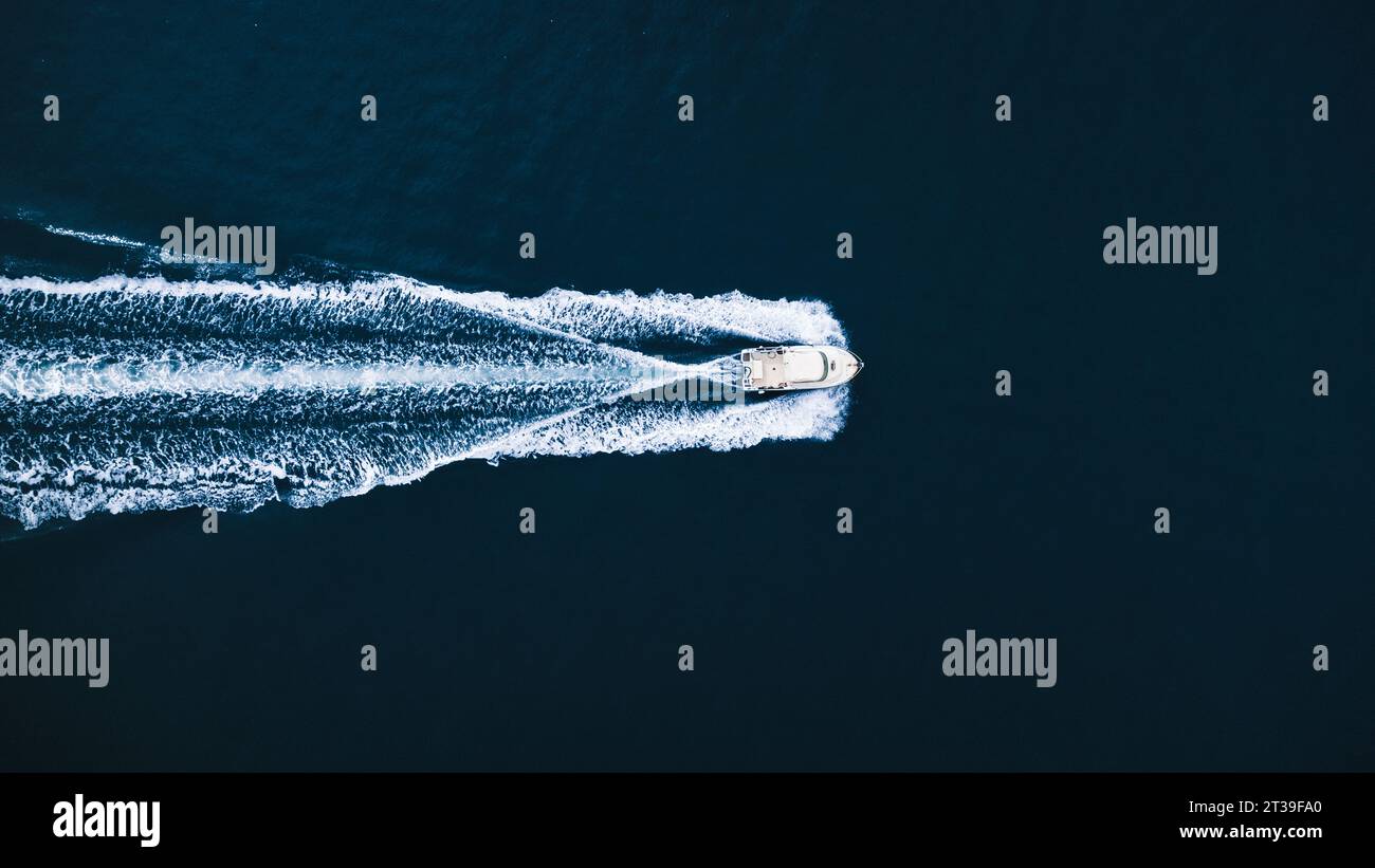 Top drone view of trail on water surface behind fast moving white ...