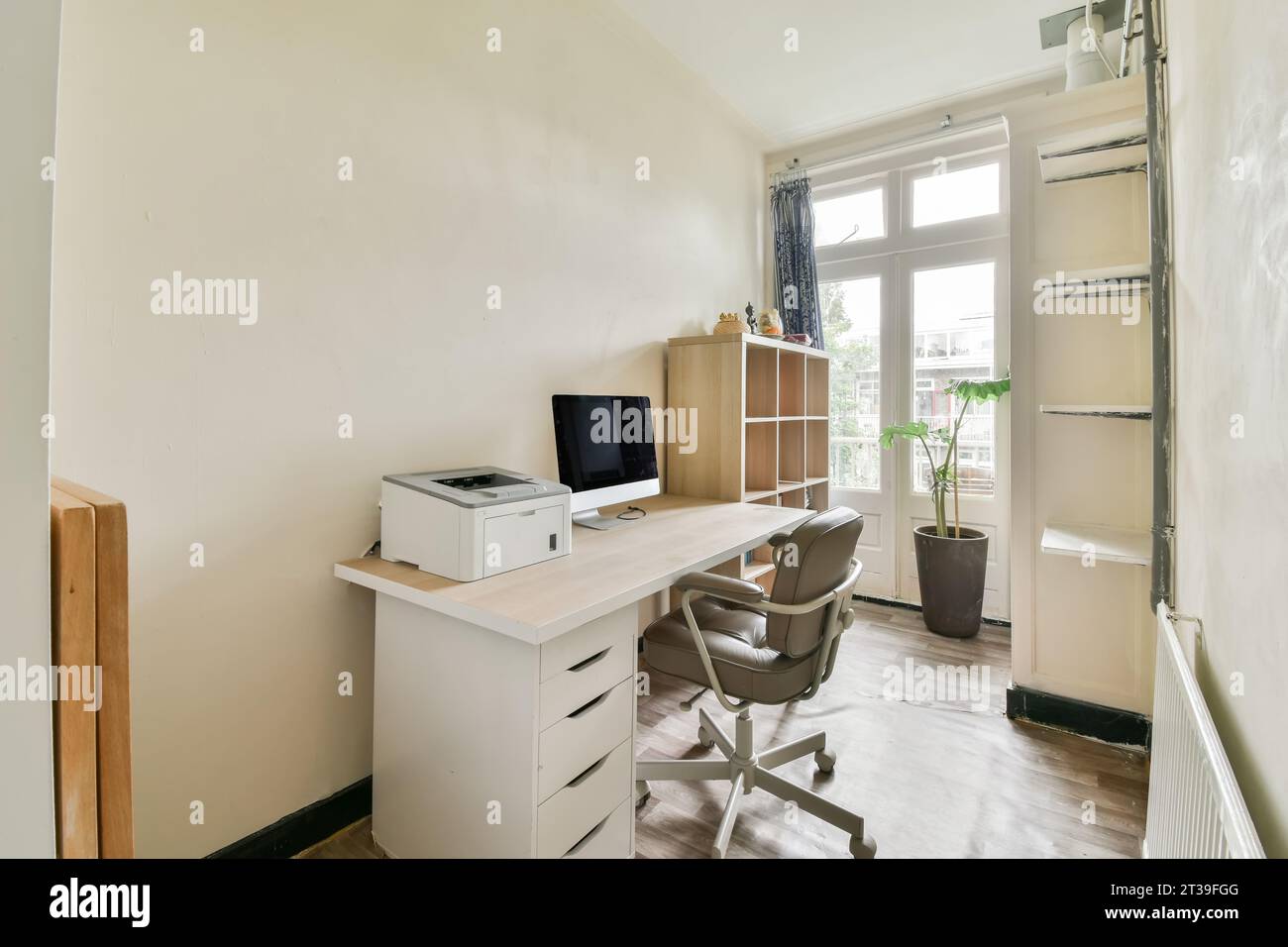 Desktop computer with printer on desk and empty chair with wooden shelf ...