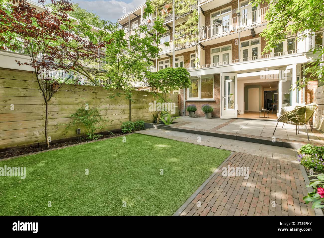 Exterior of modern apartment building with grassy lawn and tiled patio ...