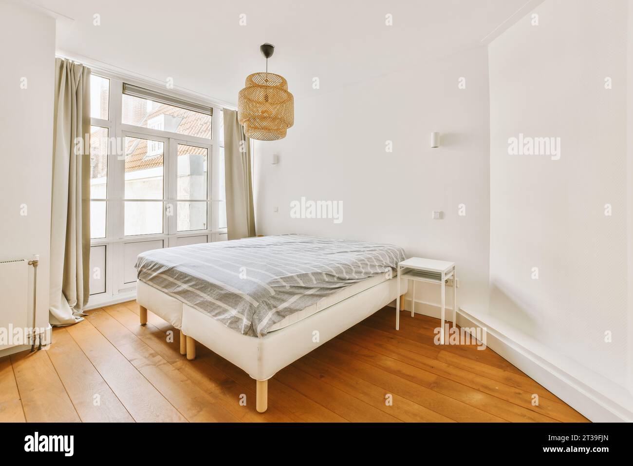 Comfortable bed with nightstand placed next to large window in spacious ...