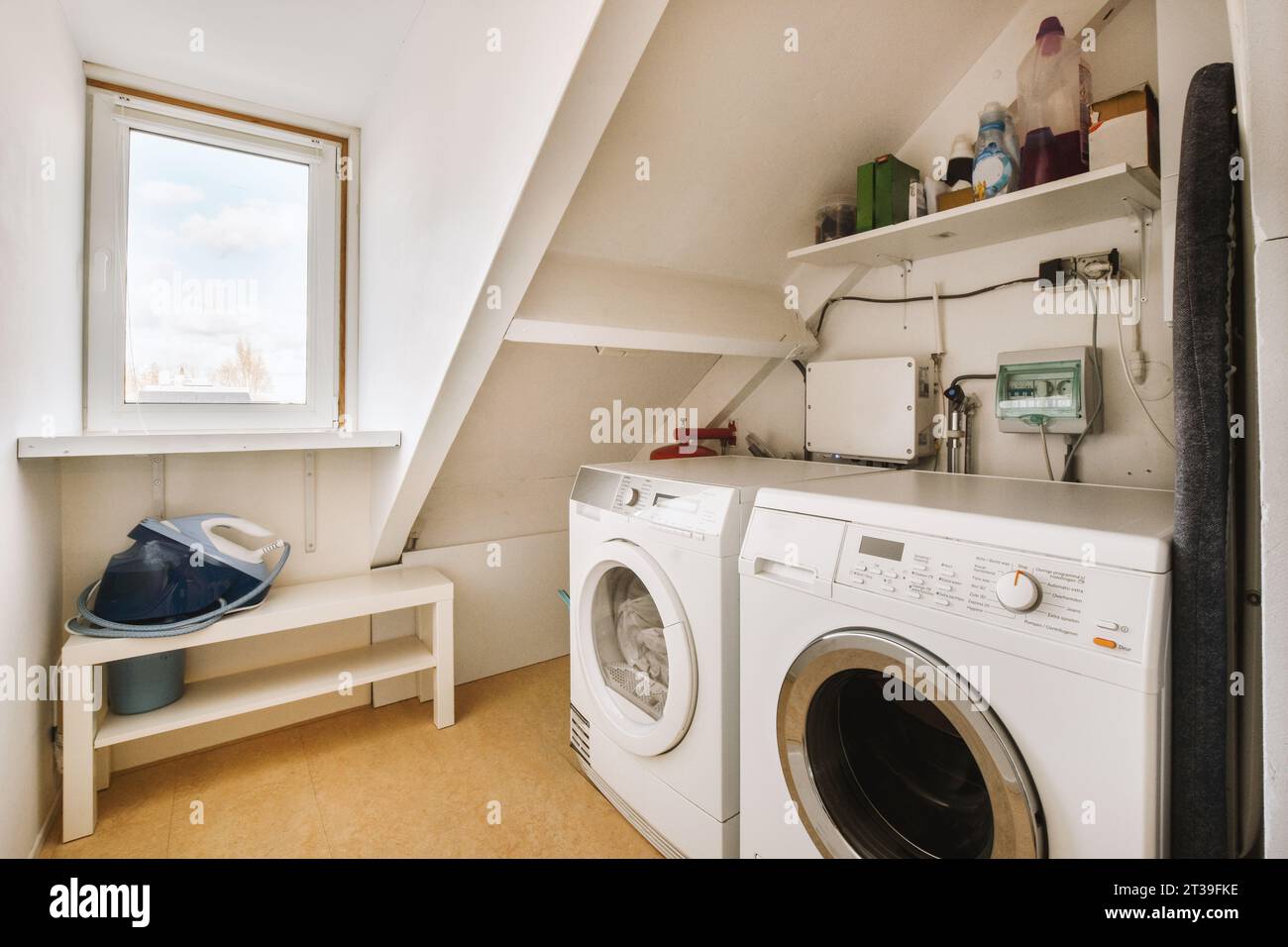 Interior of laundry room with washing and dryer machines by window with ...