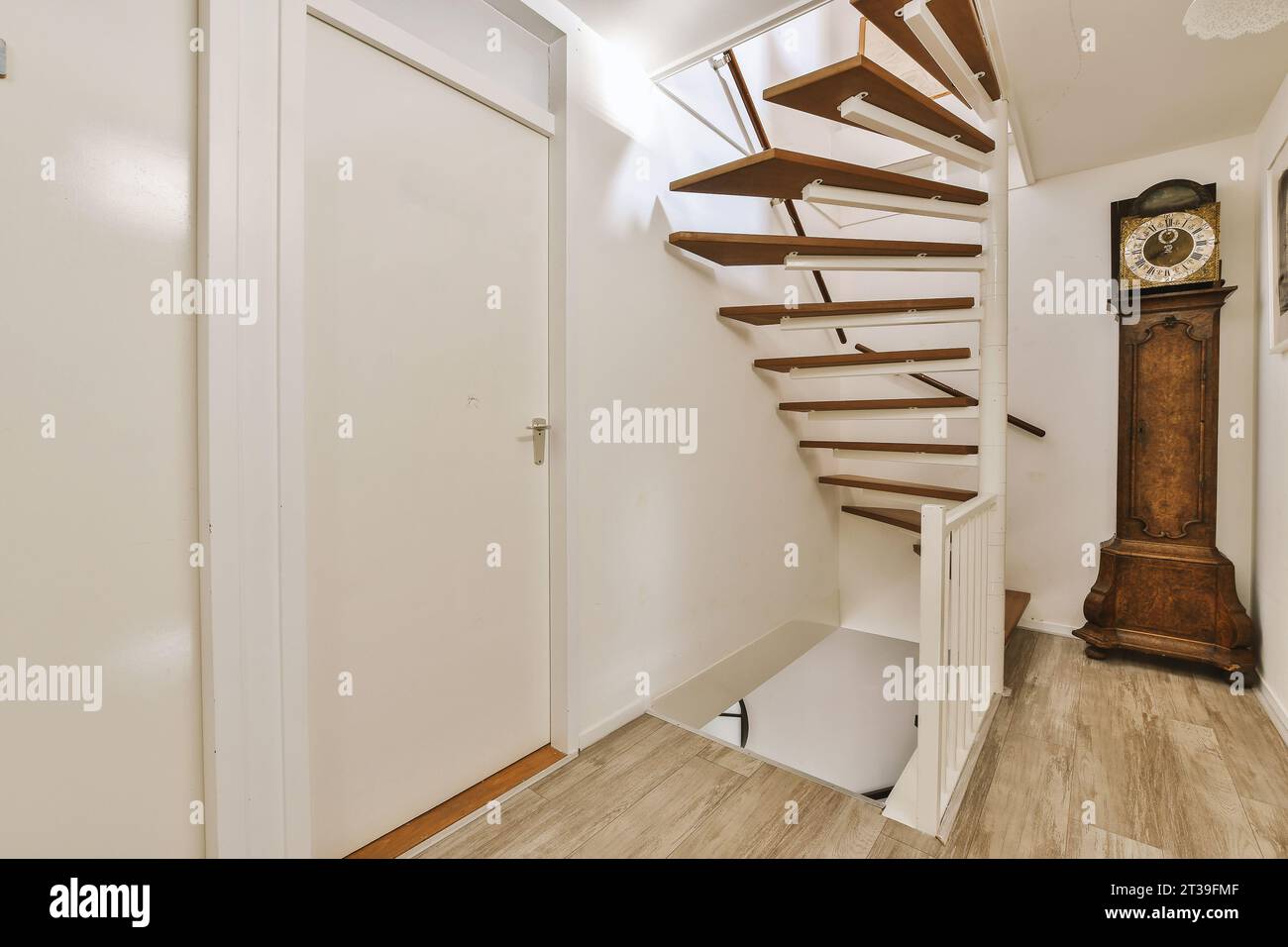 Empty hallway with spiral wooden staircase and classic grandfather ...